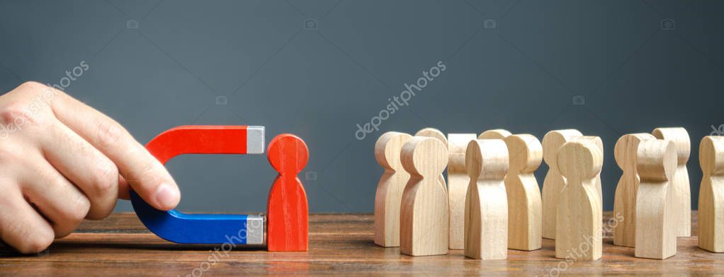 Una mano con un imán saca una figura humana roja de la multitud ...