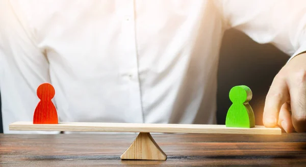 A person changes the balance of scales in favor of a green person ...