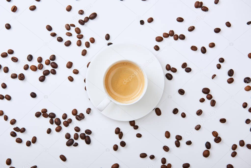 vista superior del sabroso café en taza en platillo cerca de granos ...