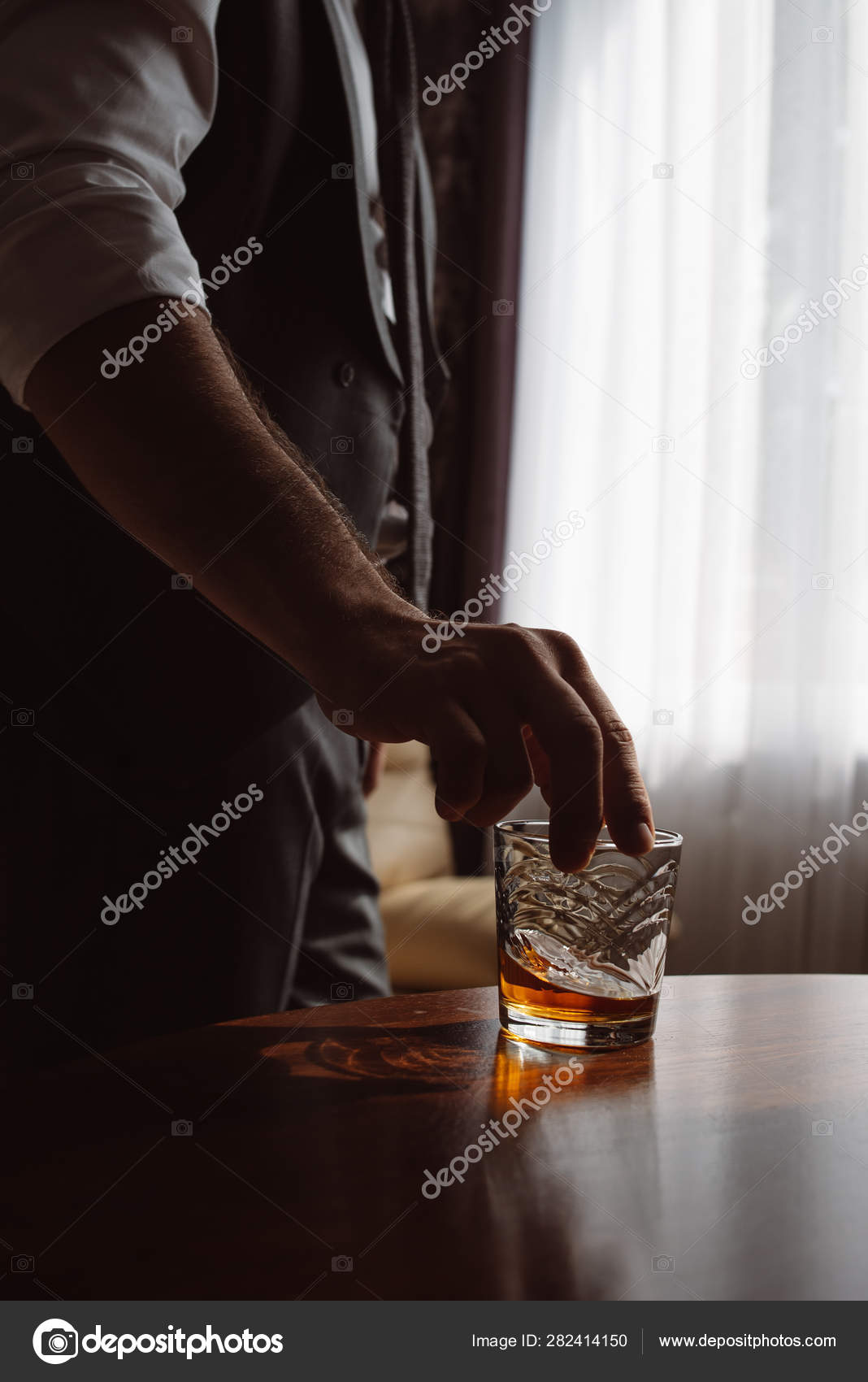 Vertical Image Of Mans Hand Holding Glass Of Whiskey Tasting And