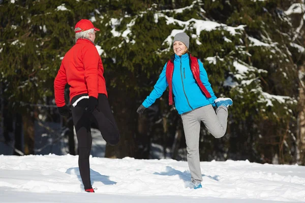 Active man and woman in sportswear standing on snow and exercising in ...