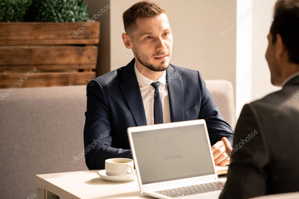 Joven solicitante de confianza en traje mirando empleador y escuchando ...