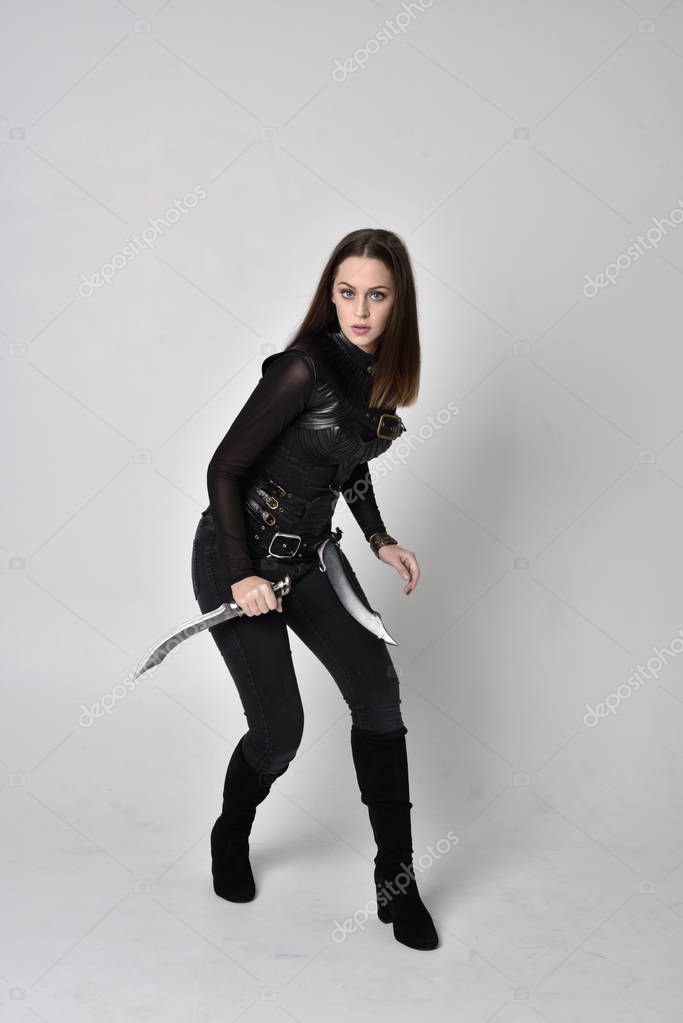 retrato de cuerpo entero de una bonita morena vestida con un disfraz de fantasía de cuero negro ...