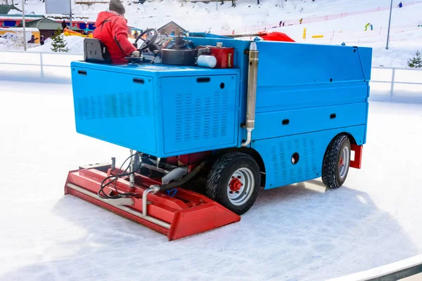A worker is shooting a special ice maintenant machine at a sports rink ...