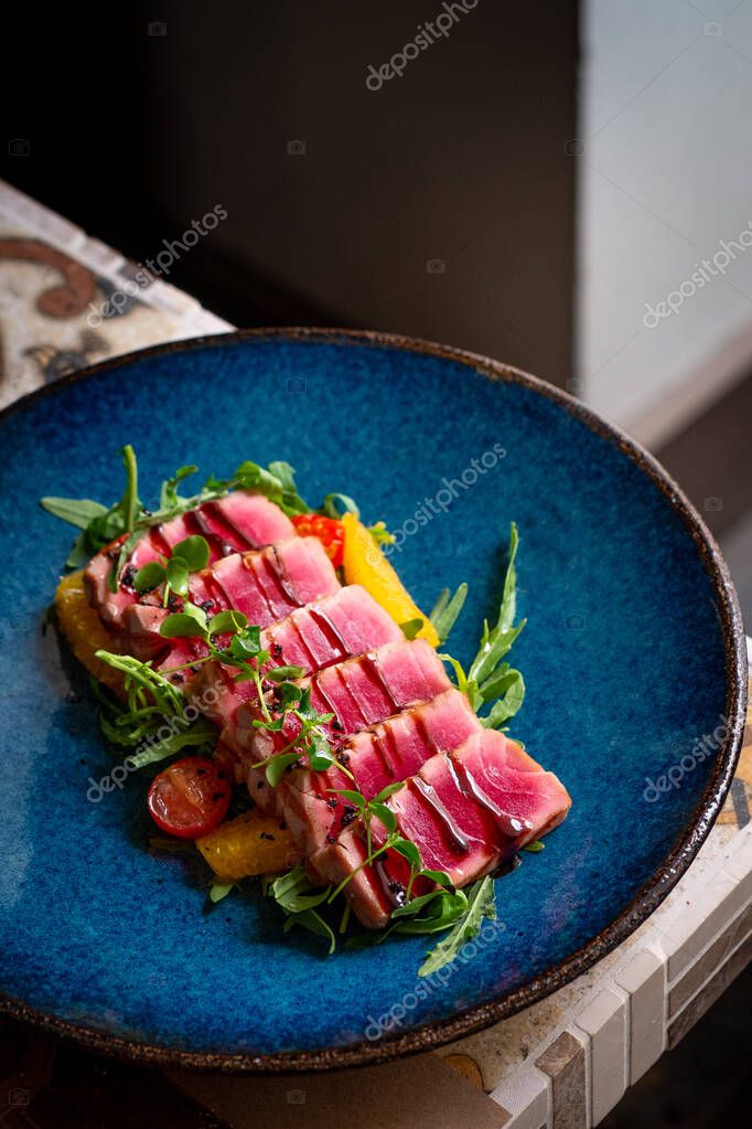 Atún a la parrilla rebanado con ensalada verde y tomates en un plato ...