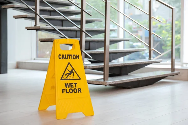 Safety sign with phrase Caution wet floor near stairs. Cleaning service ...