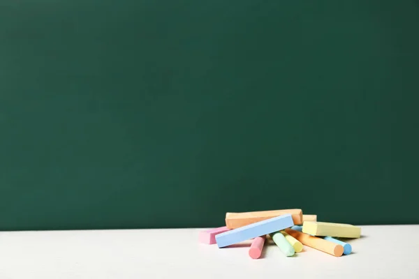 Pieces of chalk on table near board - Stock Image - Everypixel