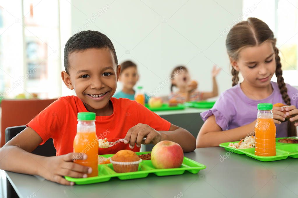 Niños sentados a la mesa y comiendo alimentos saludables durante el ...