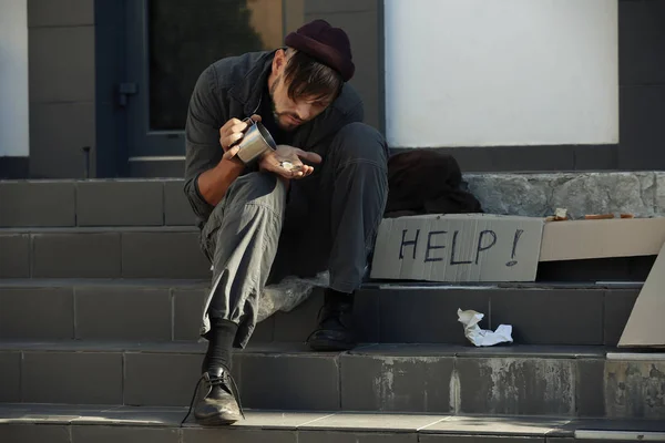 Poor senior man counting coins near cardboard sign HELP ME, closeup ...