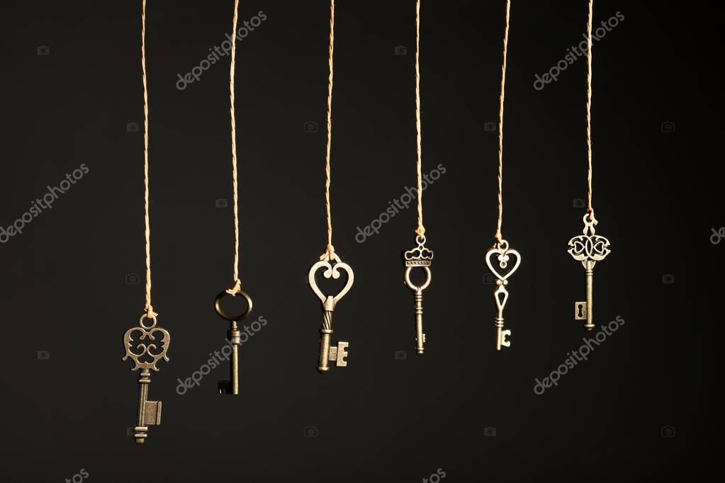 Claves adornadas vintage de bronce colgadas en hilos sobre fondo oscuro ...