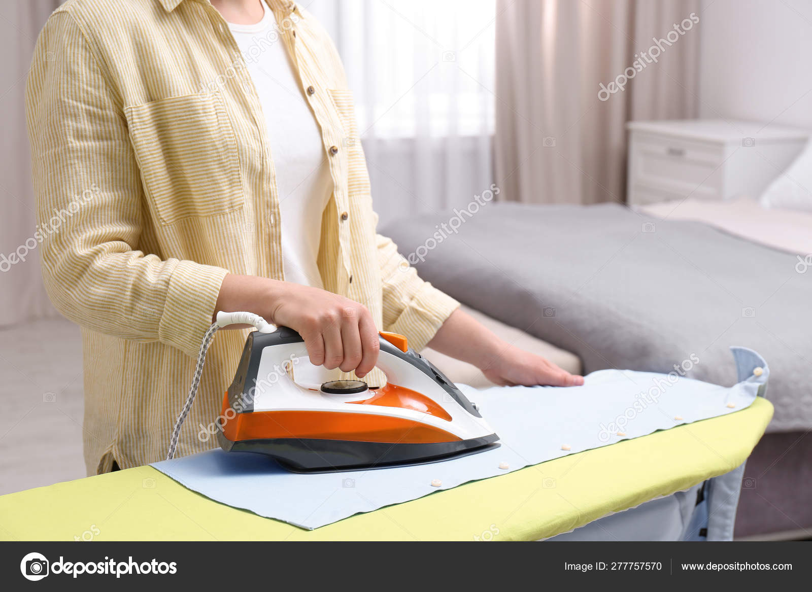 Woman ironing clothes on board in bedroom, closeup with space for text ...