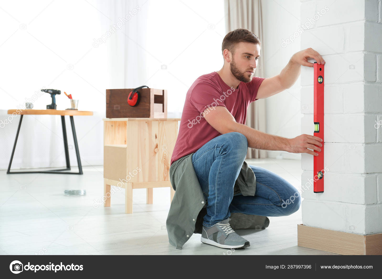 Young working man using construction level at home, space for text ...