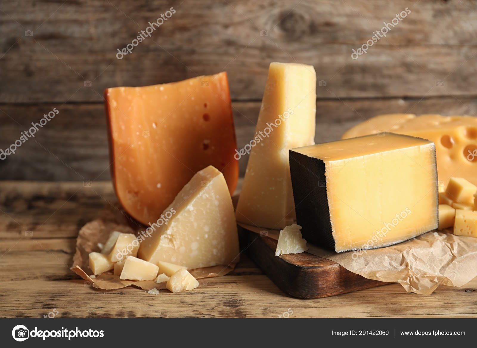 Different types of delicious cheese on table against wooden background ...