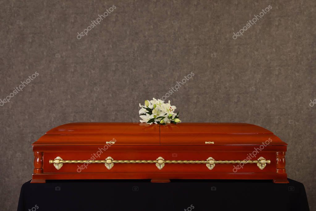 ataúd fúnebre de madera con lirios blancos en la pared gris 2023