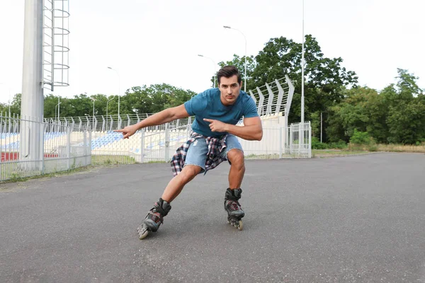 Handsome young man roller skating outdoors. Recreational activity ...