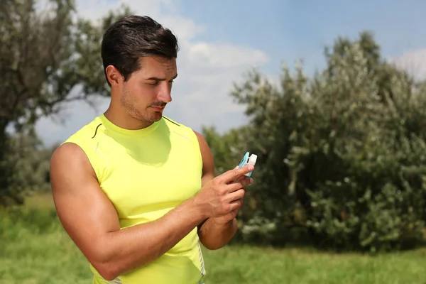 Young man checking pulse with medical device after training in park ...