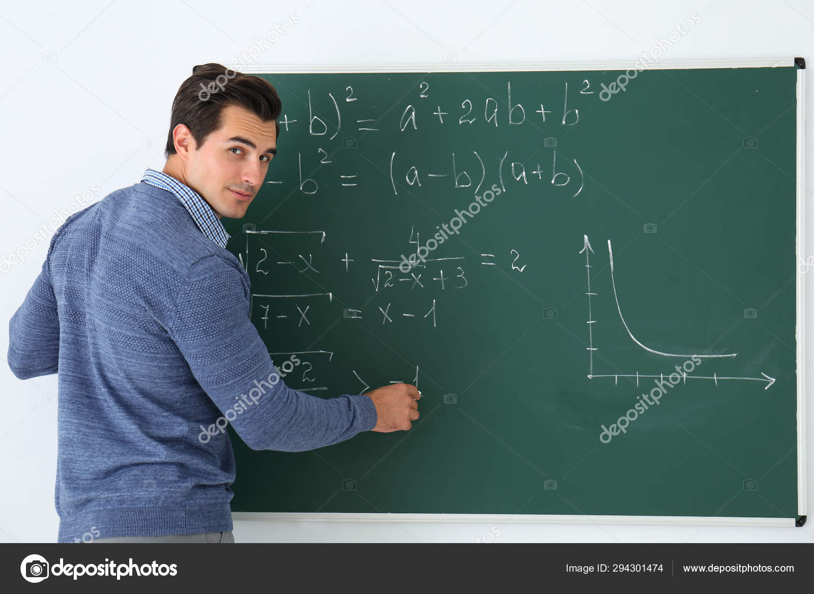 Young teacher writing math formulas on chalkboard in classroom Stock ...