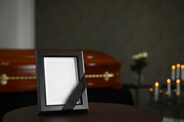 Funeral photo frame with ribbon, white rose and candle on dark table ...