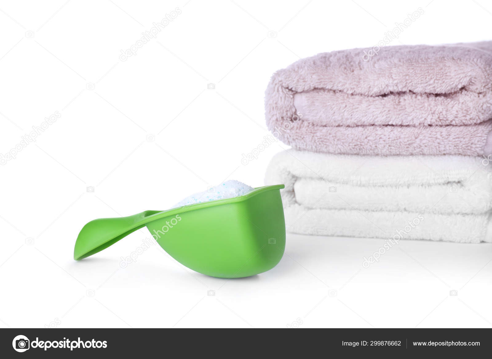 Laundry detergent in plastic measuring scoop and towels on white ...