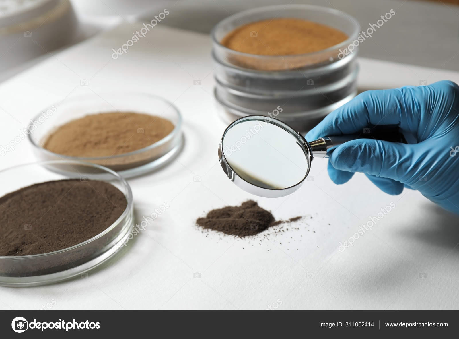 Scientist examining soil sample with magnifier at table, closeup ...