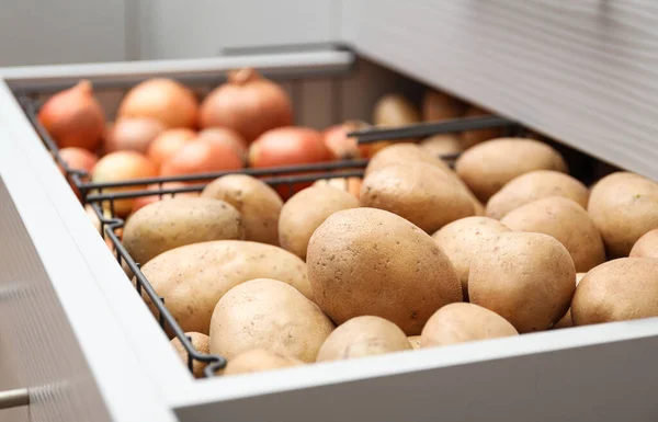 Open drawer with potatoes and onions, closeup. Orderly storage Stock ...