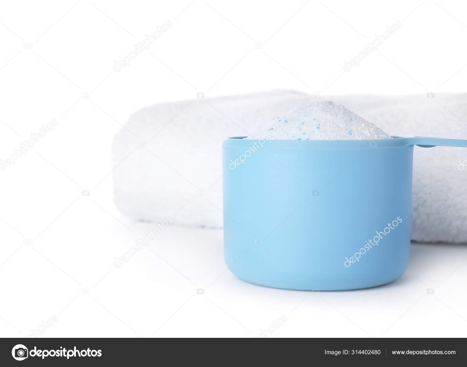 Laundry detergent in plastic measuring scoop and towel on white ...