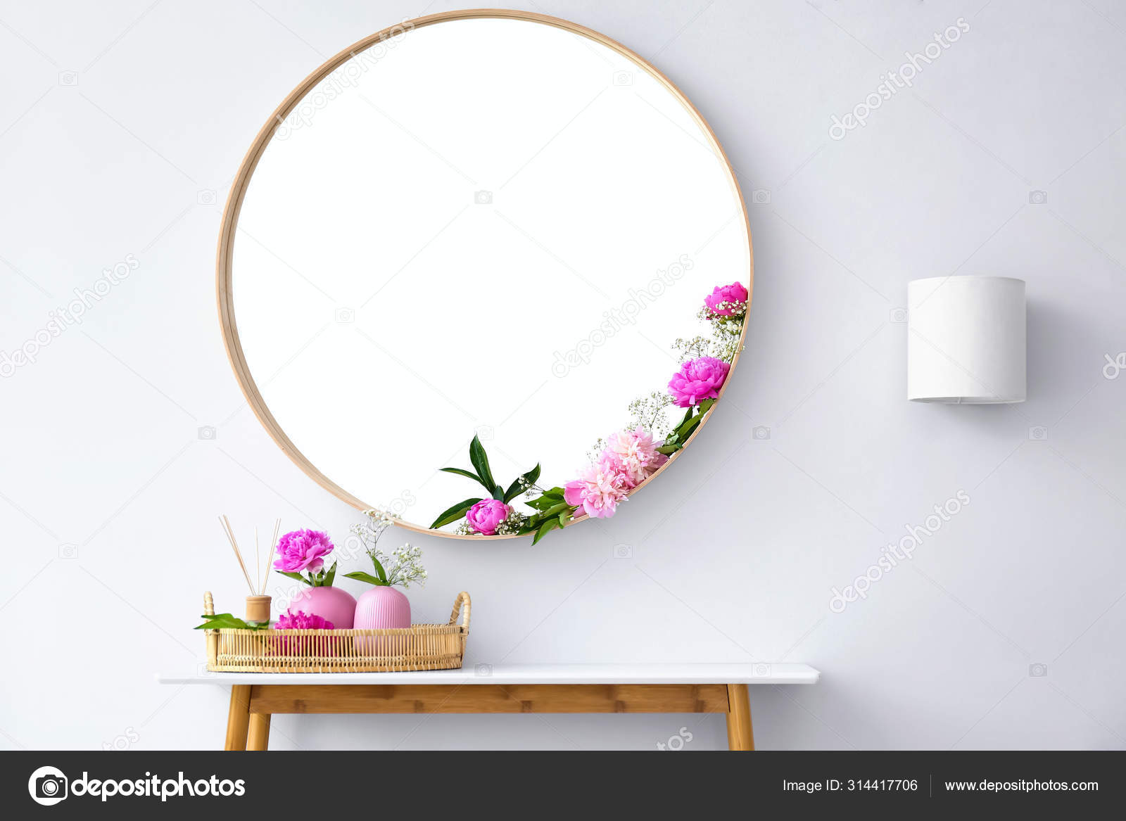 Round mirror and table with accessories near white wall in modern room ...