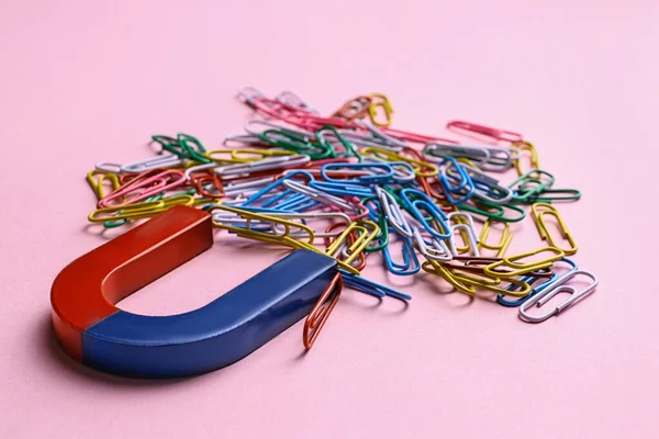 Horseshoe magnet attracting paper clips on white background Stock Photo ...