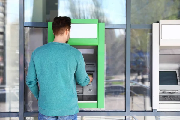 Young man using modern cash machine outdoors Stock Photo by ©NewAfrica ...