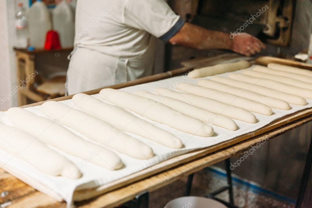 Baker está preparando el pan crudo de masa antes de hornear en un horno ...
