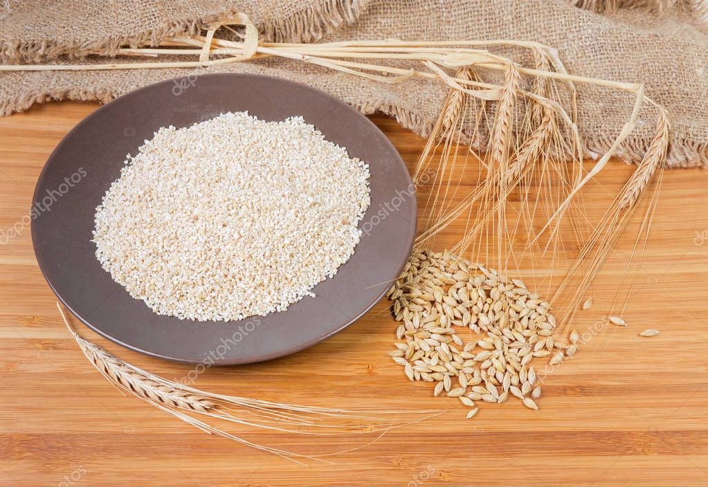 Grano crudo de cebada molida fina en el plato de cerámica marrón ...