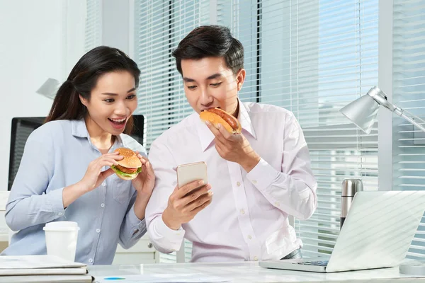 Business people eating fast food and reading exciting news on ...