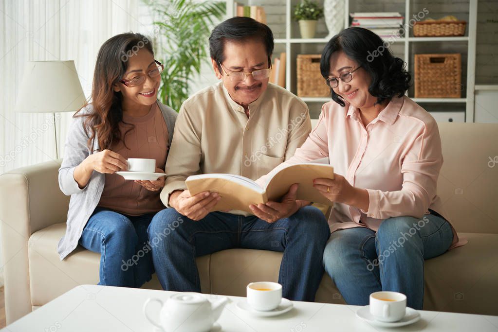 Personas mayores tomando té y hojeando el álbum de fotos con fotos ...