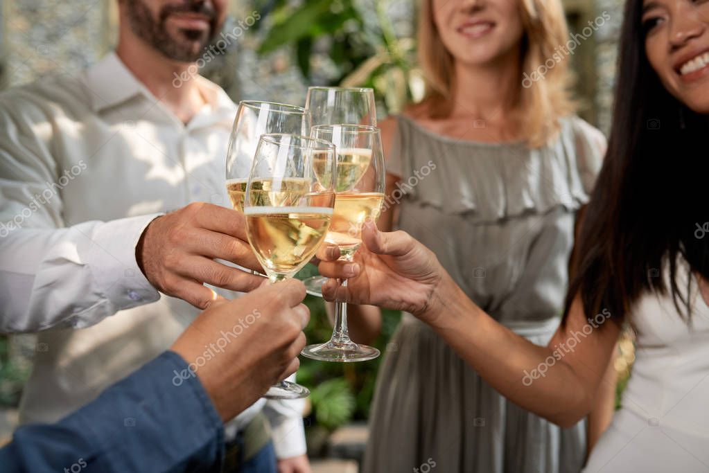 Manos de invitados tintineando vasos en la fiesta de cóctel 2024