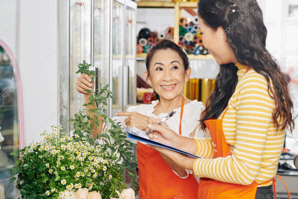 Floristería vietnamita y su asistente discutiendo cómo cuidar la planta ...