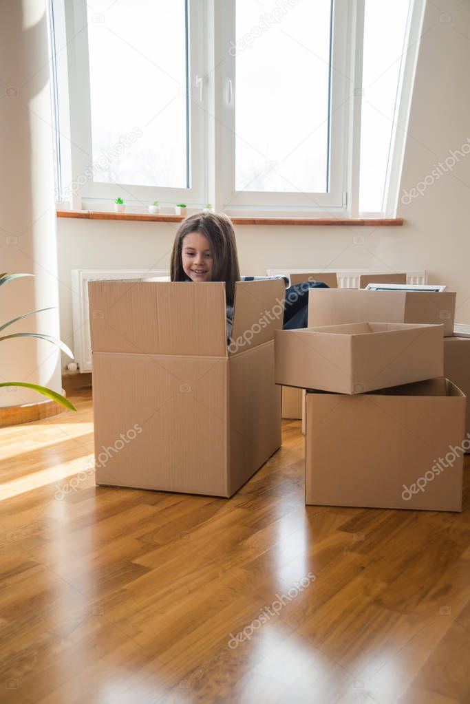 feliz niño hija en caja emocionado acerca de mover día o reubicación, alegre chica jugando ...