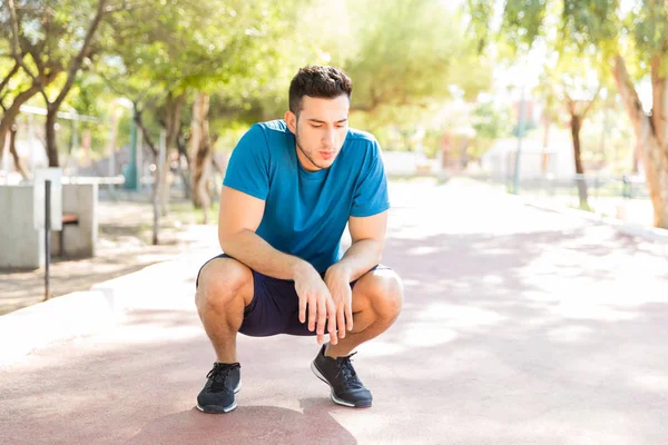Determined male runner crouching on track after workout in park - Stock ...