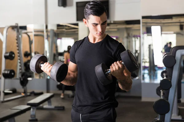 Dedicated male athlete showing devotion towards his body in health club ...