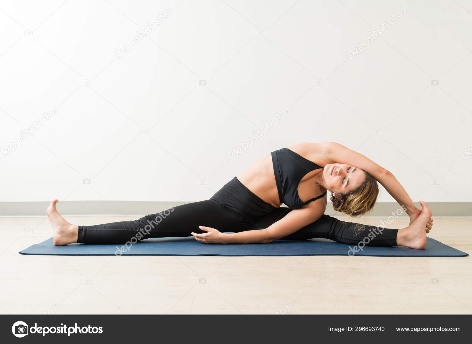 Flexible Young Pretty Female Stretching While Sitting Astride Exercise ...