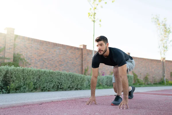 Young determined man in start position in public park - Stock Image ...