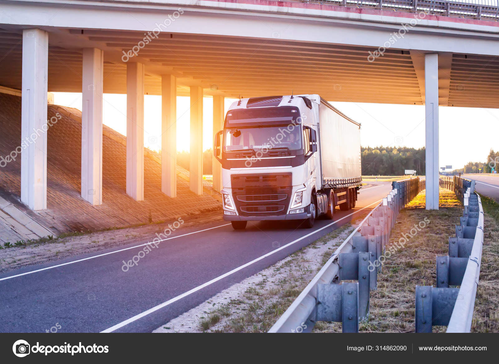 An international driver is carrying goods on a wagon under a bridge ...