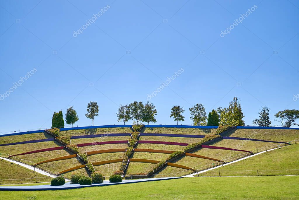 Una pequeña colina decorada con escalones de colores, arbustos y ...
