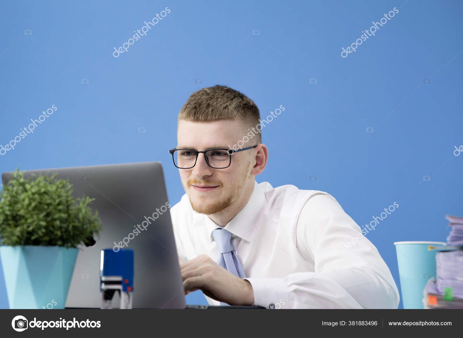 Young smiling office worker works enthusiastically and intently at a ...
