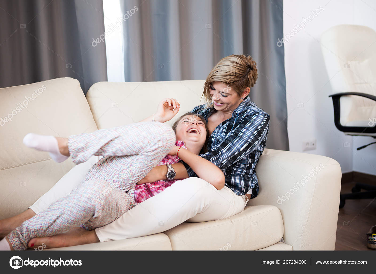 Happy teenage child daughter and her mother laughing on the couch ...