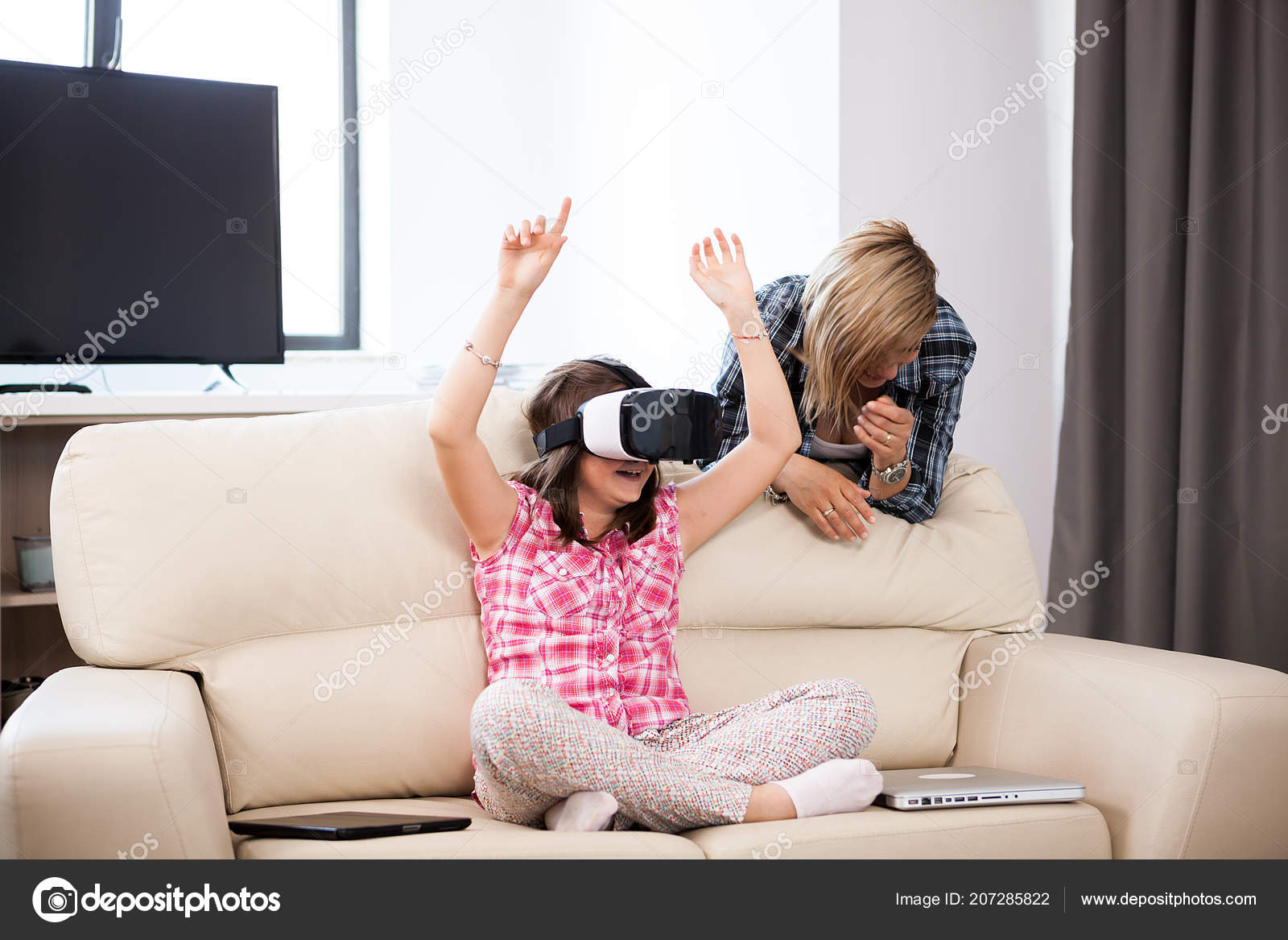 Mother in the living room sitting next to her daughter that is wearing ...