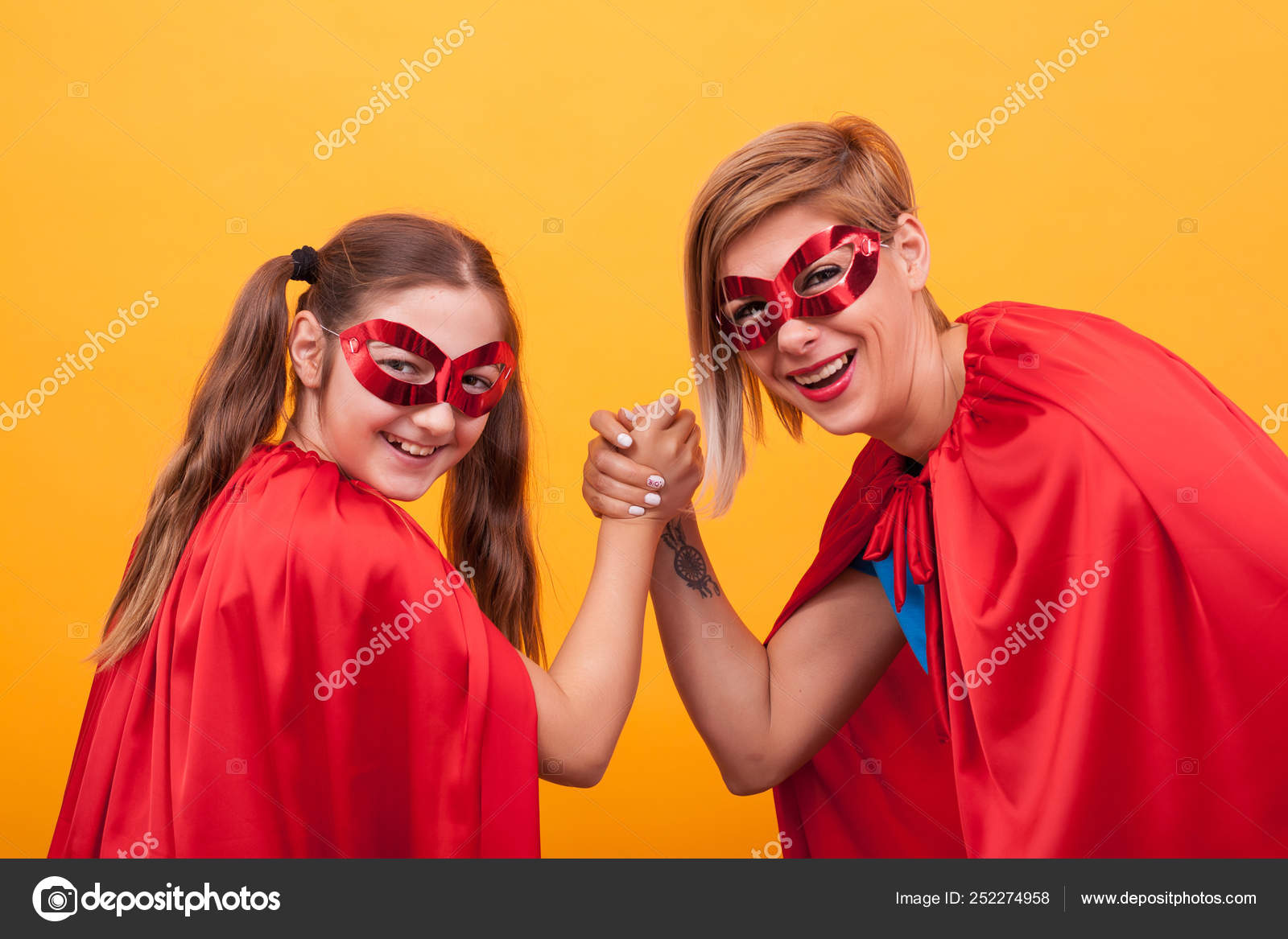 Mother and daughter dressed like superheroes playing arm wrestling over ...