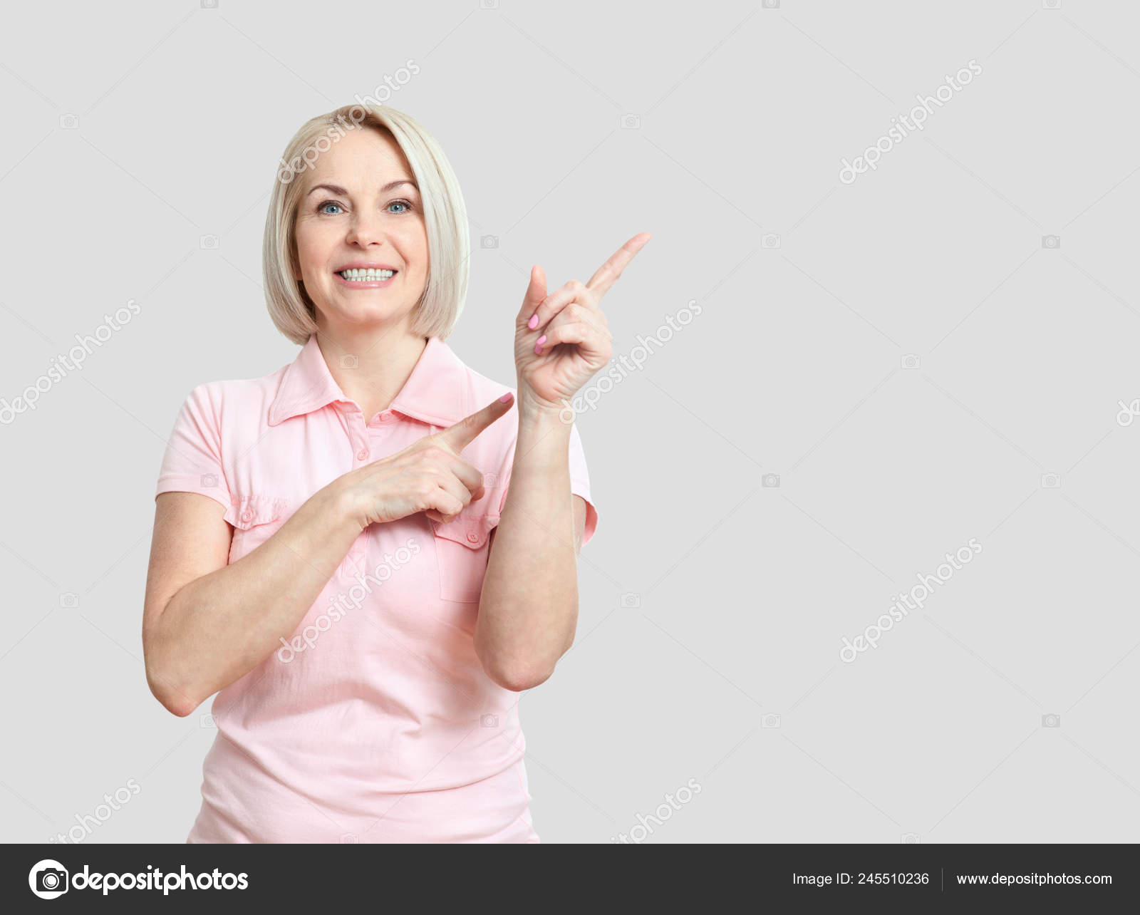 Friendly smiling middle aged woman pointing at copyspace isolate Stock ...