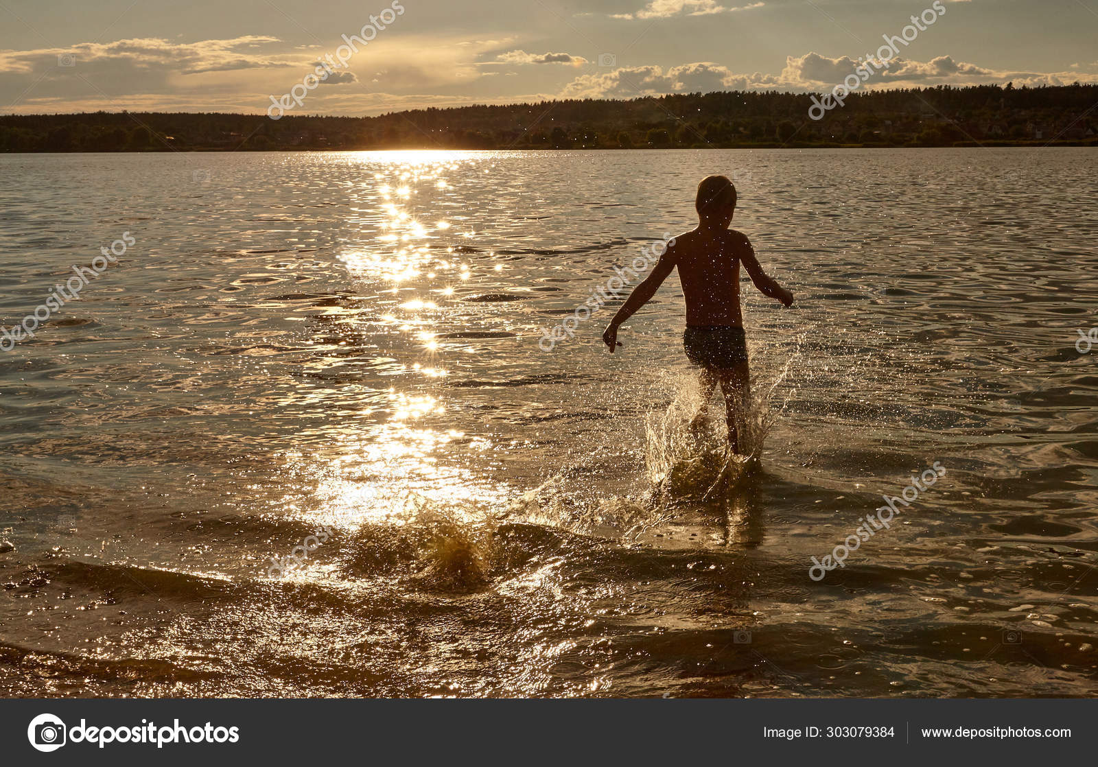 Silhouette of a boy running through the water in the rays of the Stock ...