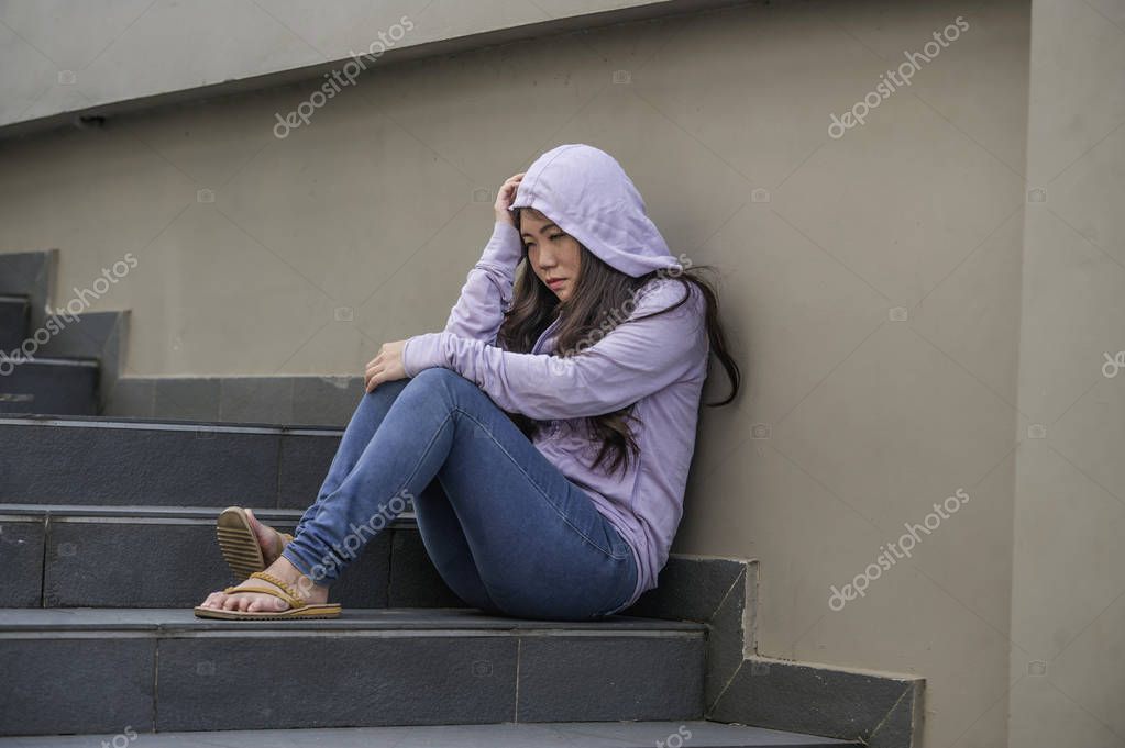 joven triste y deprimido asi tico chino estudiante mujer o intimidado adolescente sentado al ...