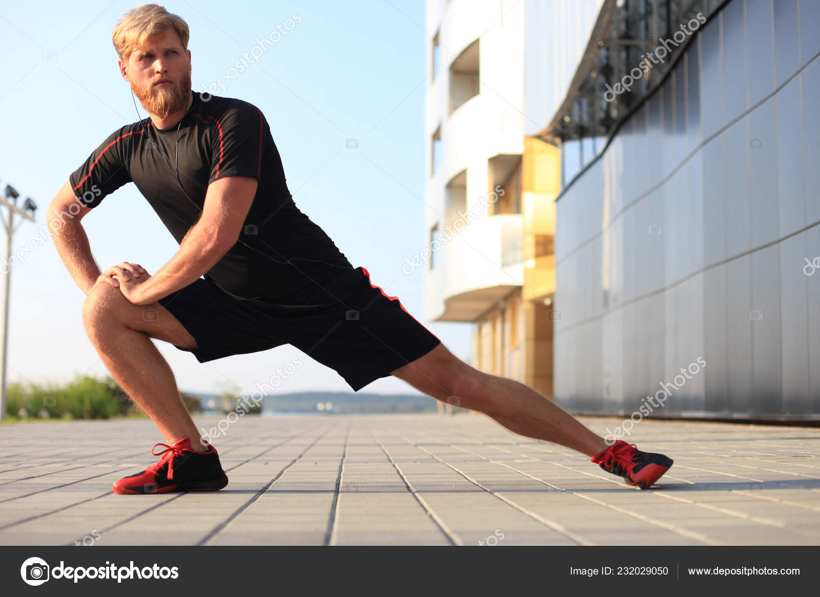 Handsome young man doing stretching exercises before running while ...